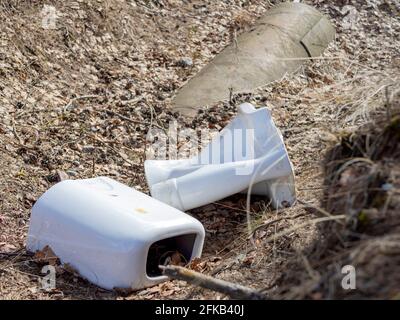 Broken ceramic toilet discarded in a swamp with other garbage Stock ...