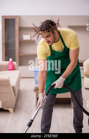 Young male contractor wearing prickly wreath on head doing housework ...