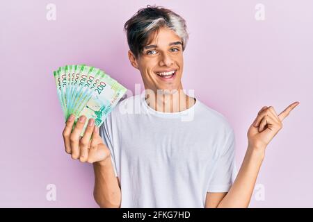 Young hispanic man holding russian 500 ruble banknotes smiling happy ...
