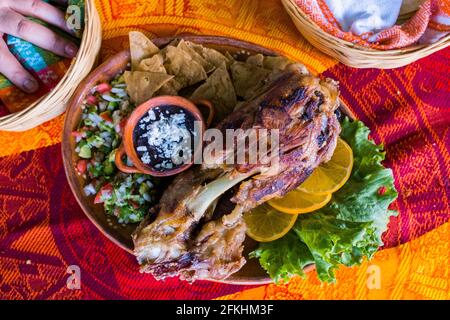 Roasted meat with vegetables and refried beans on colorful tablecloth ...