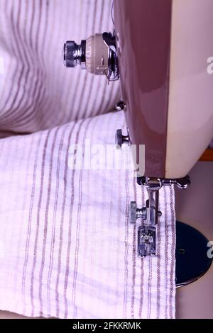 Sewing machine in use with striped fabric and sewing tools arranged ...