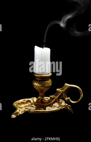 Still life with an extinguished candle in an old brass candlestick and ...