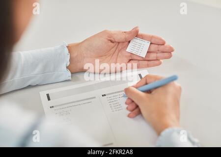 Closeup of unrecognizable student hiding cheat note while taking exam ...
