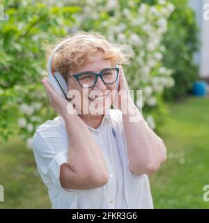 Contented elderly woman enjoys music and holds hands on headphones ...