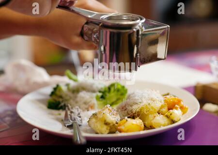 Hand grating cheese with a cheese grater onto a plate Stock Photo - Alamy