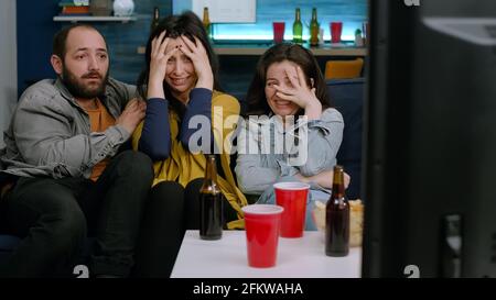 Multi-racial friends screaming while watching thriller horror movie ...