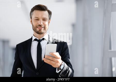 Happy entrepreneur reading emails from business partners in airport ...