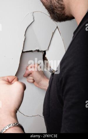The angry man hits the wall and breaks it Stock Photo - Alamy