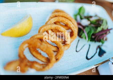 Fried Calamari rings with rosemary and lemon Stock Photo - Alamy