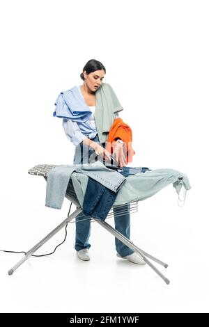 full length of brunette housewife in apron adjusting heeled sandal and ...