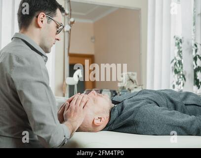 Craniosacral therapy practitioner giving a male patient CST osteopathic ...