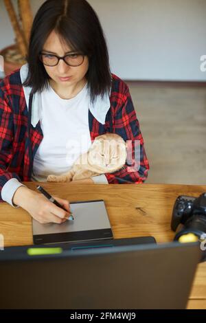 retoucher with cat using graphic tablet while working at computer ...