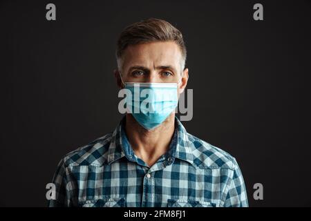 Photo of serious grey-haired man wearing face mask isolated over grey ...