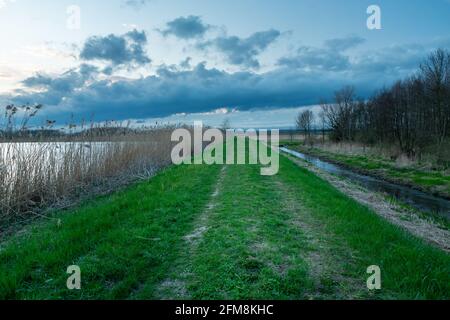 An earth embankment with a path by the Uherka river and the lake ...