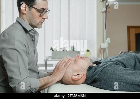 Craniosacral therapy practitioner giving a male patient CST osteopathic ...