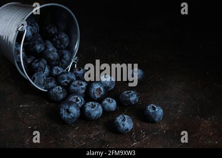 Blueberry berries spilled from metal bucket onto wooden table Stock ...