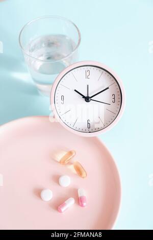 Clock with pills and glass of water on table in room, closeup Stock ...