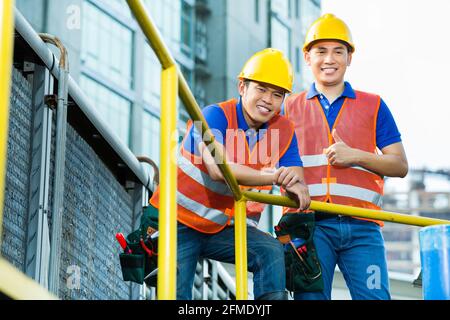 Asian Indonesian construction workers with helmet and safety vest on a ...
