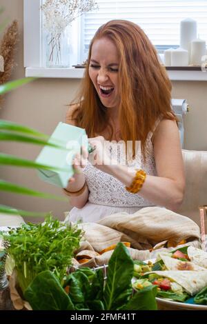 smiling redhead woman with present box on yellow background. happy ...