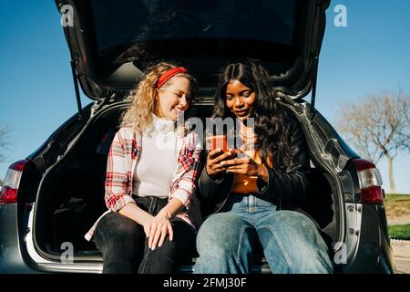 Low angle of cheerful multiracial female best friends embracing in ...