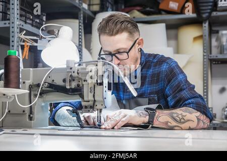 Male artisan using sewing machine while creating upholstery for ...