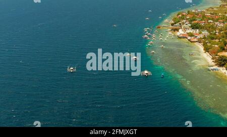 Shore with hotels near coral reef and diving boats, Moalboal ...