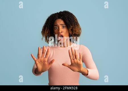 Shocked black lady showing stop gesture at camera, refusing something ...