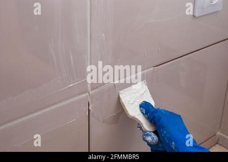 Repair and wall cladding with tiles. The master rubbing the tile joints ...