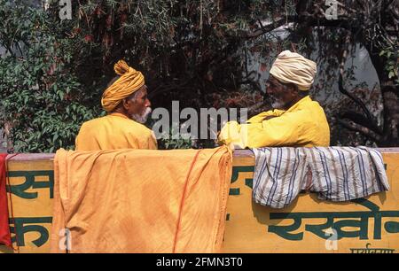 Bearded Indian men sit and talk next to a shrine in Varanasi, India. A ...