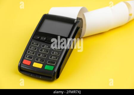 Payment terminal POS with a roll cash tape on the yellow background ...