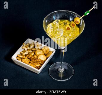 Martini, a glass with spicy olives, on a dark background. Alcoholic ...