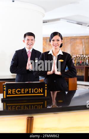 Hotel front office team welcoming and registering guest at reception ...