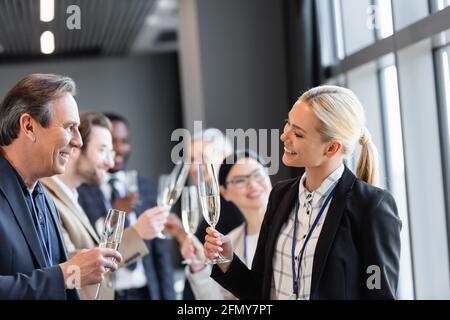 Interracial business people holding glasses of champagne near balloons ...