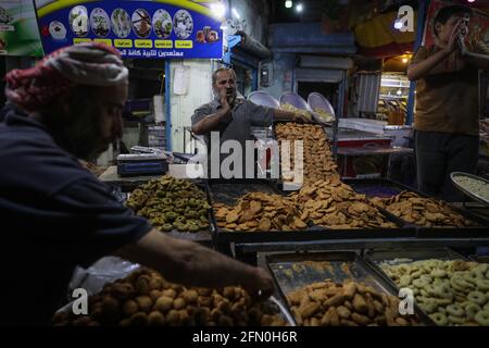 Idlib, Syria. 13th May, 2021. A vendor sells food in a street market in ...
