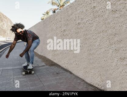 African american man riding longboard with beach in the background ...