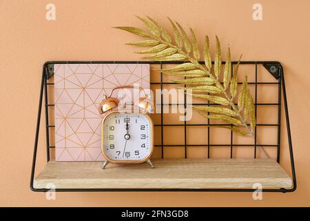 Shelf with alarm clock and decor hanging on color wall Stock Photo - Alamy