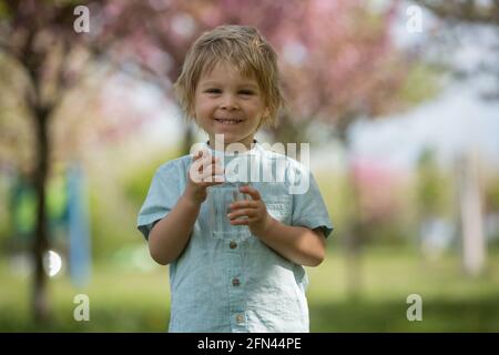 Beautiful blond child, boy, drinking water in the park on a hot summer ...
