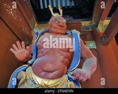 Statue of a Shinto deity in a Japanese mausoleum. Red statue of Raijin ...