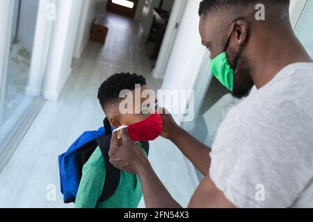 African american father and son putting on face masks Stock Photo - Alamy