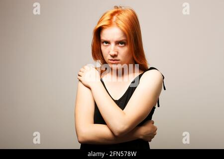 Beautiful fragile redheaded young woman in the dark. Sad frightened ...