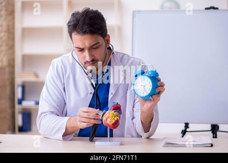 Young doctor cardiologist in time management concept Stock Photo - Alamy