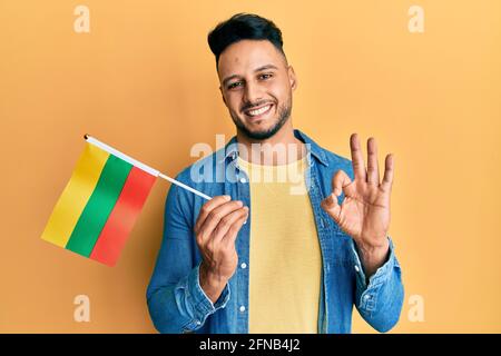 Young arab man holding lithuania flag smiling with an idea or question ...