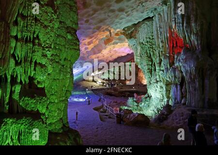 Visitors in a large cave with stalactite and stalagmite formations, Dau ...