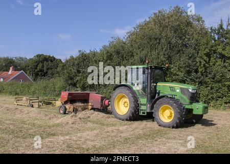 Haymaking, third stage, conventional baler moves bales in sleds Stock ...