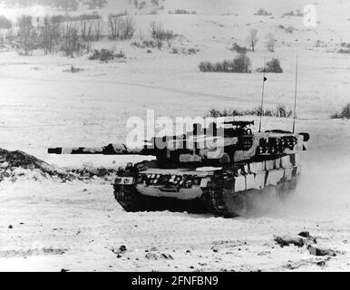 A German Leopard 2 tank in winter camouflage and a Ukraine flag on its ...