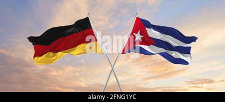 Cuba and Germany flags waving together in the wind on blue cloudy sky ...