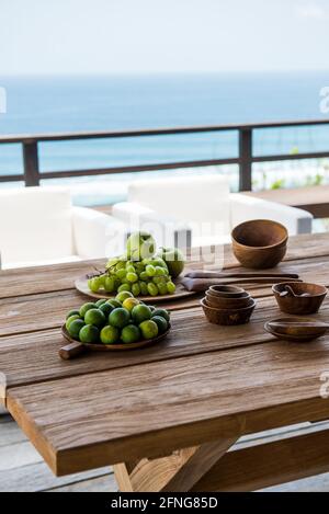 Fresh green sea grapes served in a sleek black bowl, surrounded by red ...