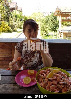 Woman eating shrimp and drinking beer Stock Photo - Alamy