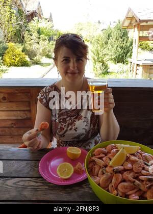 Woman eating shrimp and drinking beer Stock Photo - Alamy