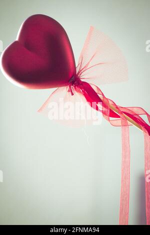 Red heart attached to a stick with a bow hanging. Copy space Stock ...